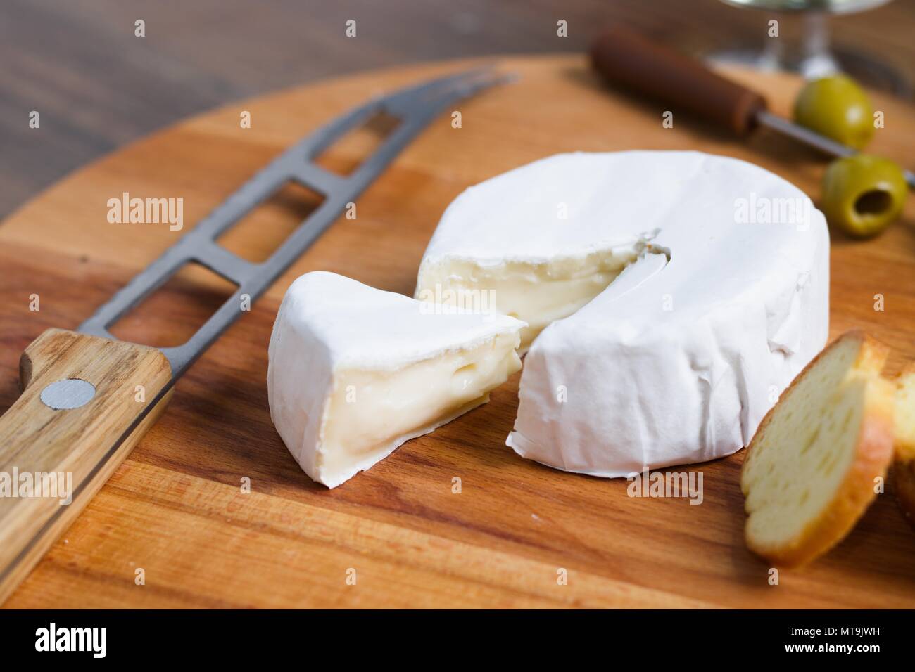 Soft cheese with white rind (camembert or brie) on wooden board with ...