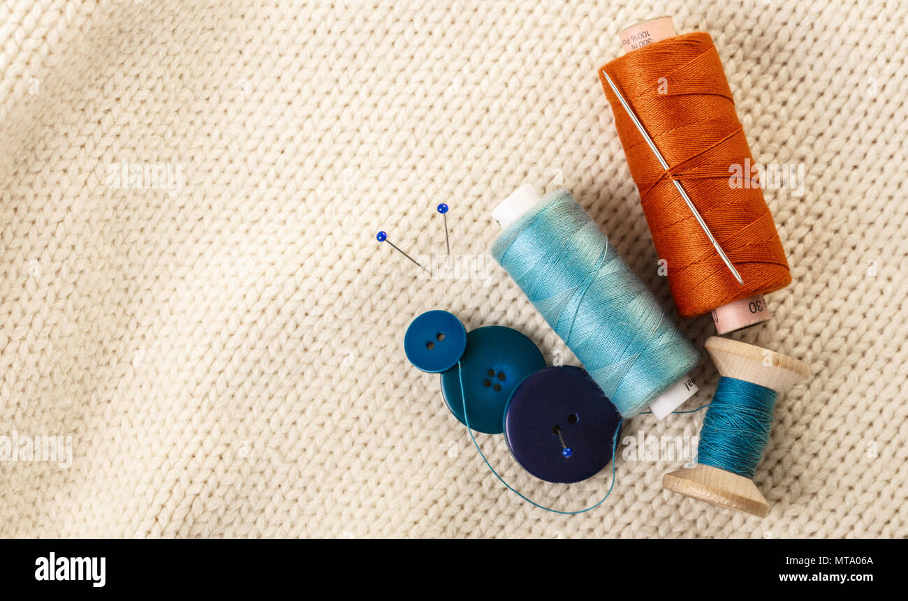 colored thread and buttons on white knitted fabric Stock Photo - Alamy