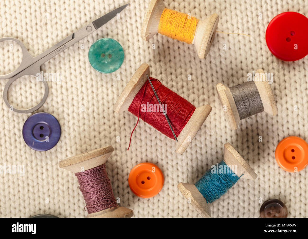 colorful threads and buttons on white knitted fabric Stock Photo - Alamy