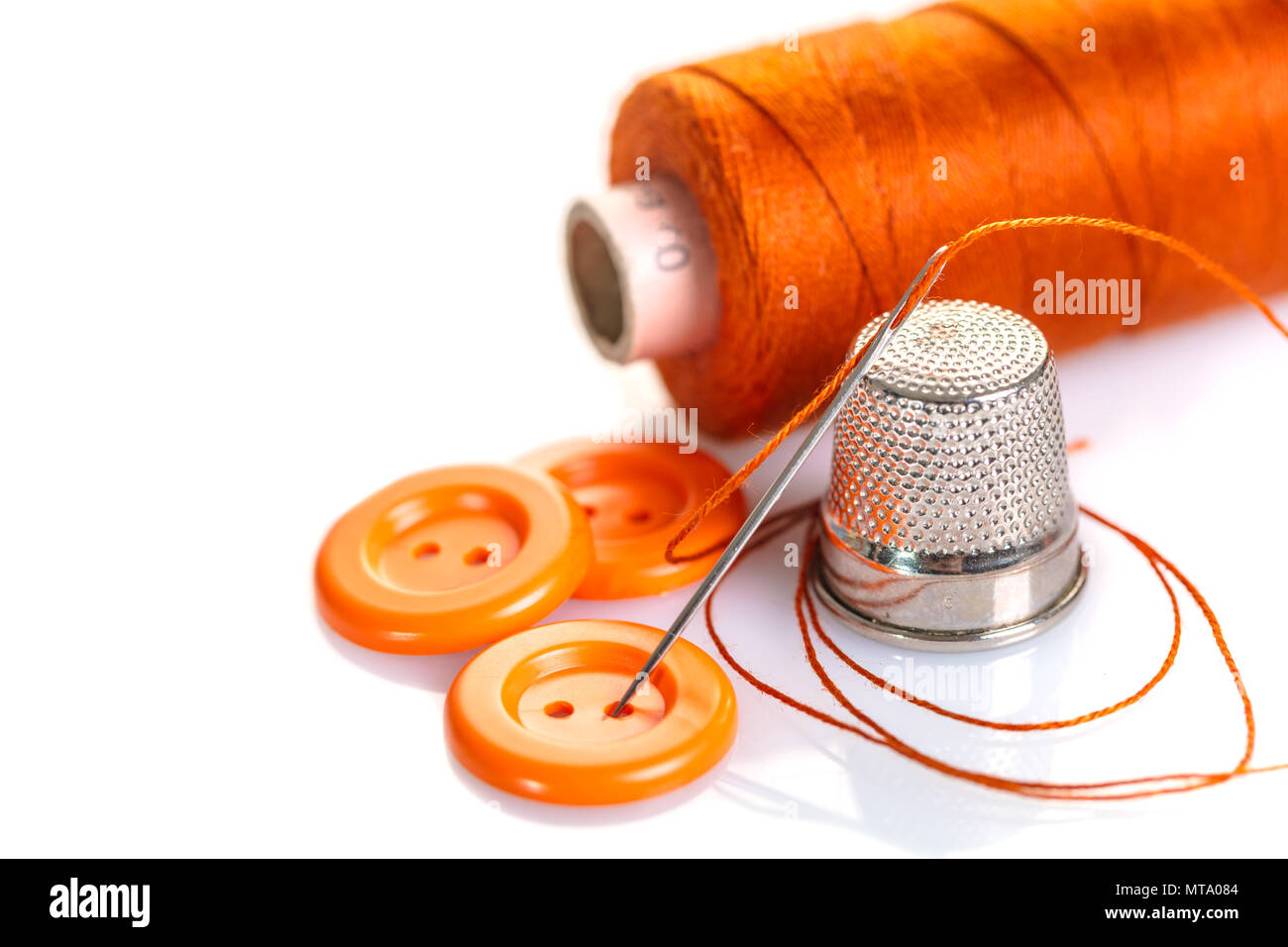 Needle with orange thread and buttons on a white background Stock Photo ...