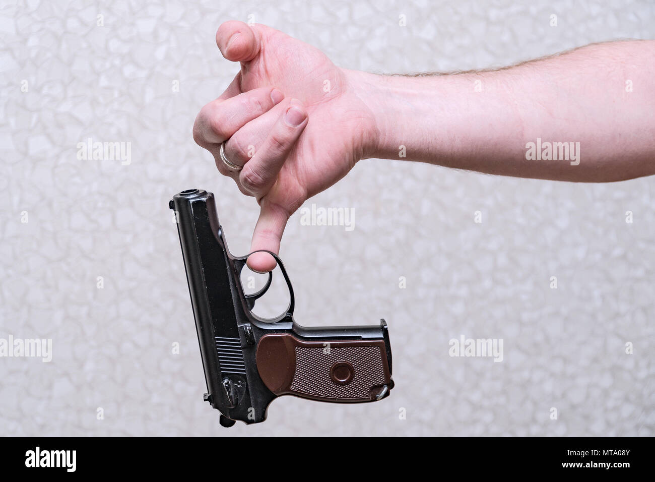 Gun hangs on a man's finger on a gray background Stock Photo - Alamy