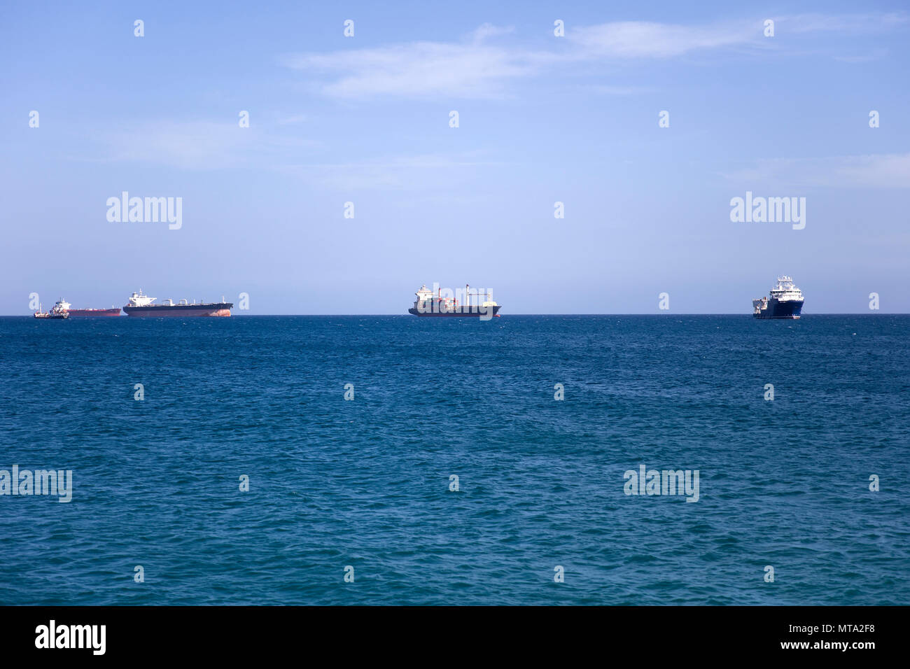 Cargo ships on the horizon of blue sea Stock Photo - Alamy
