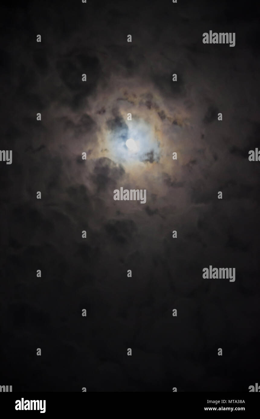 Dark photo of bright full moon in between dramatic clouds during the ...