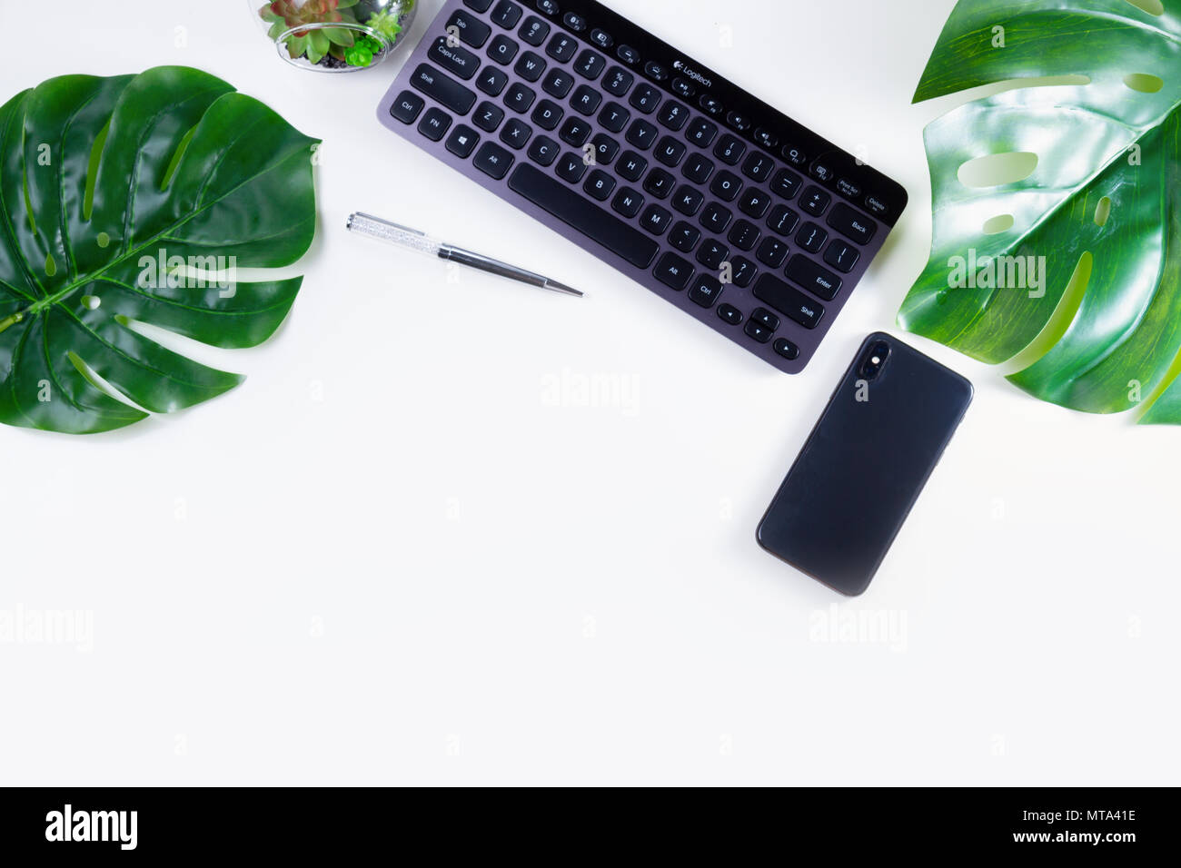 Flat lay home office workspace with black keyboard and green monstera ...