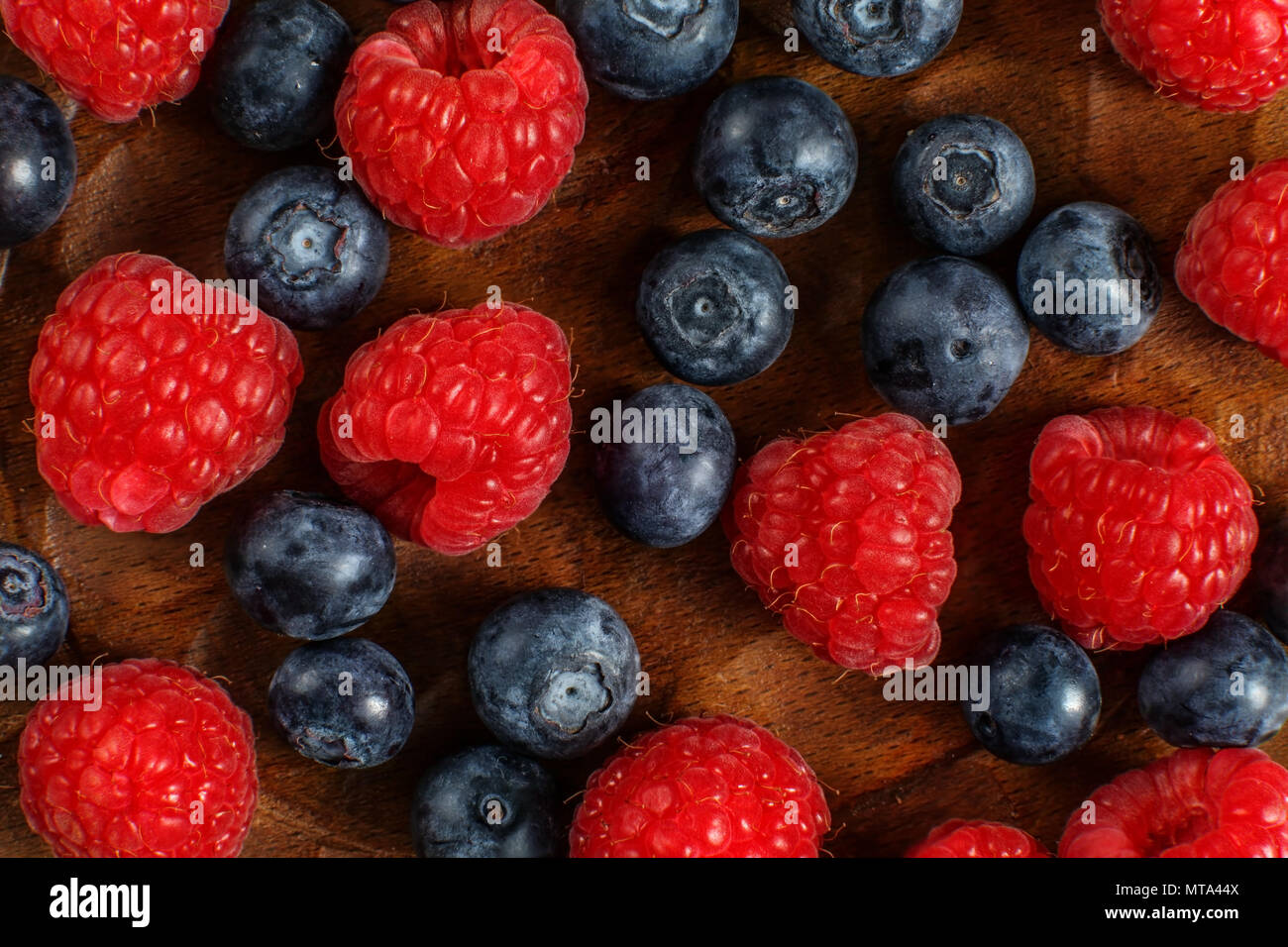 Detail top view on mixed blueberries and raspberries on wooden plate ...