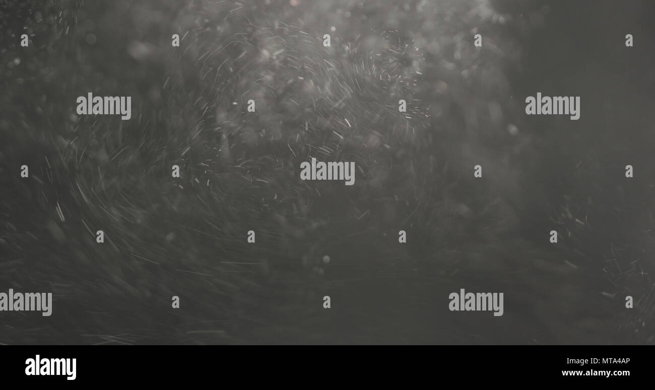 dust particles floating over black background with motion blur, wide ...