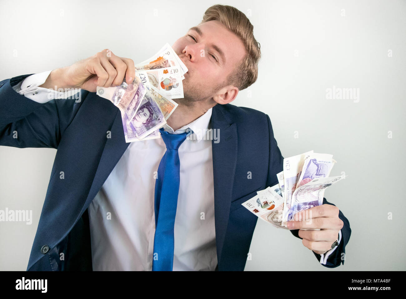 Happy man in suit holding wads of money of pound sterling banknotes in ...