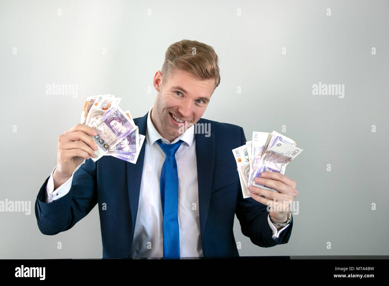 Happy man in suit holding wads of money of pound sterling banknotes in ...