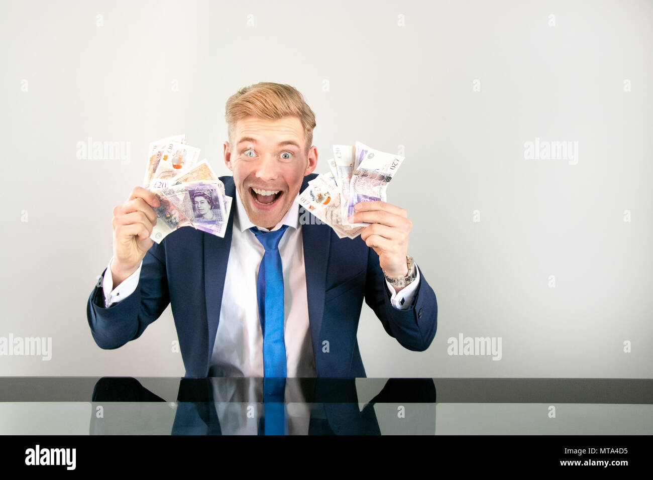 Happy man in suit holding wads of money of pound sterling banknotes in ...