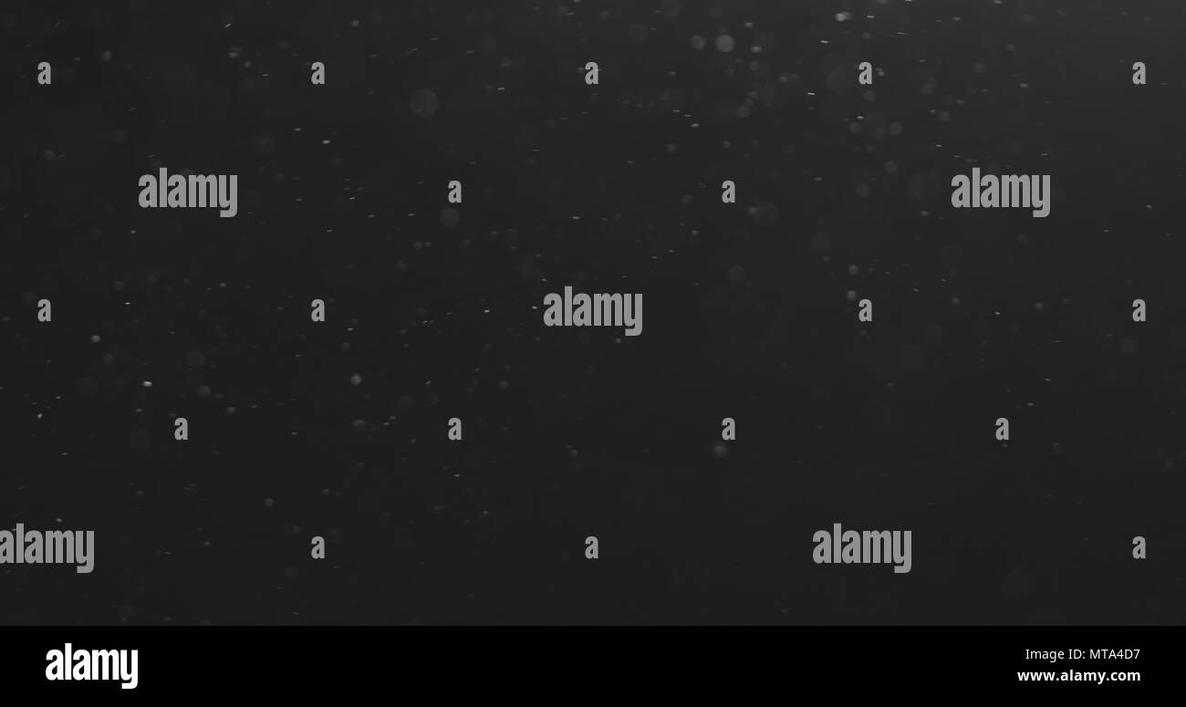 dust particles floating over black background with motion blur, wide ...