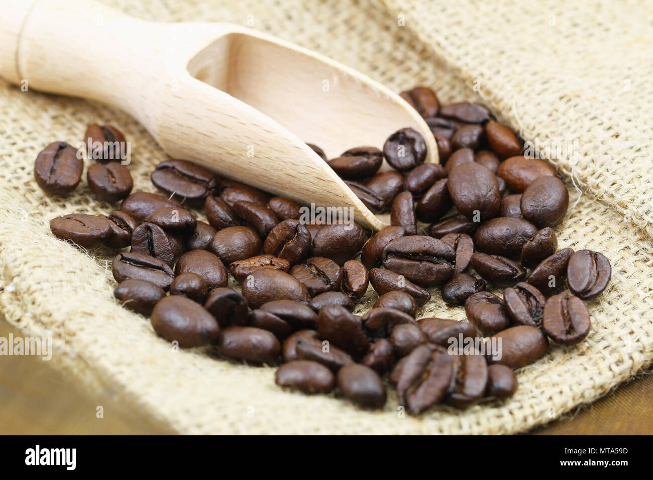 Roasted coffee beans on wooden scoop and jute bag Stock Photo - Alamy