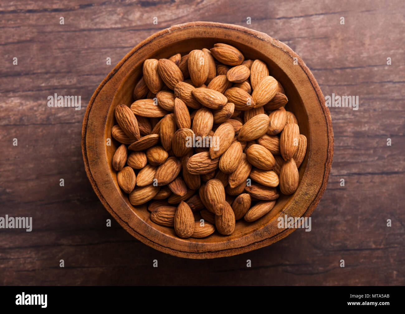 Wooden bowl with fresh raw almond nuts on wooden background Stock Photo ...