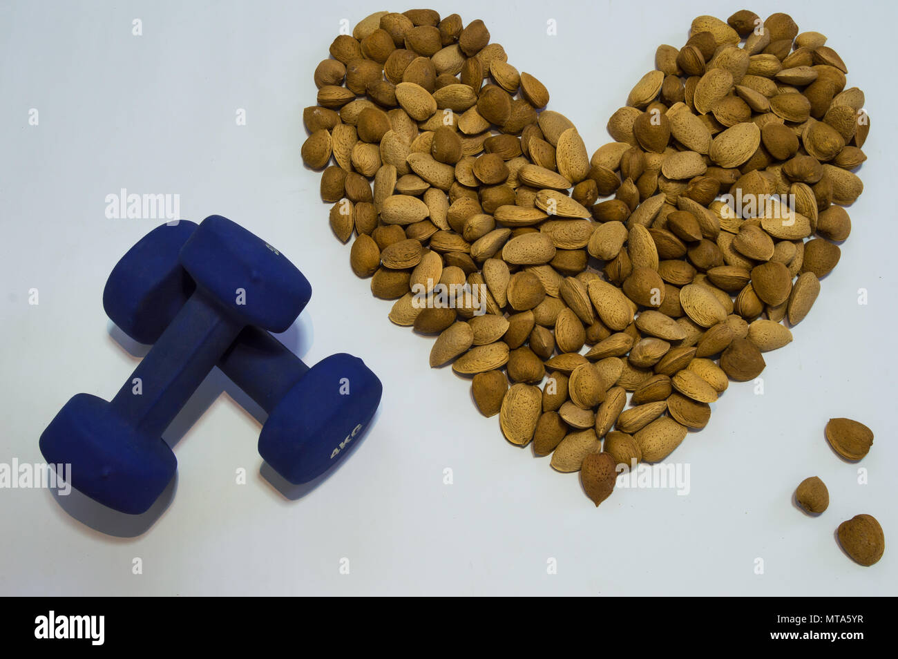 Heart made with almonds with peel and a pair of blue dumbbells. Concept ...