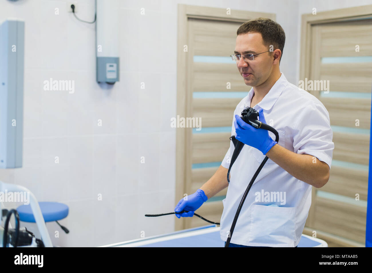 Proctologist holding an anoscope against a proctological chair. In the ...