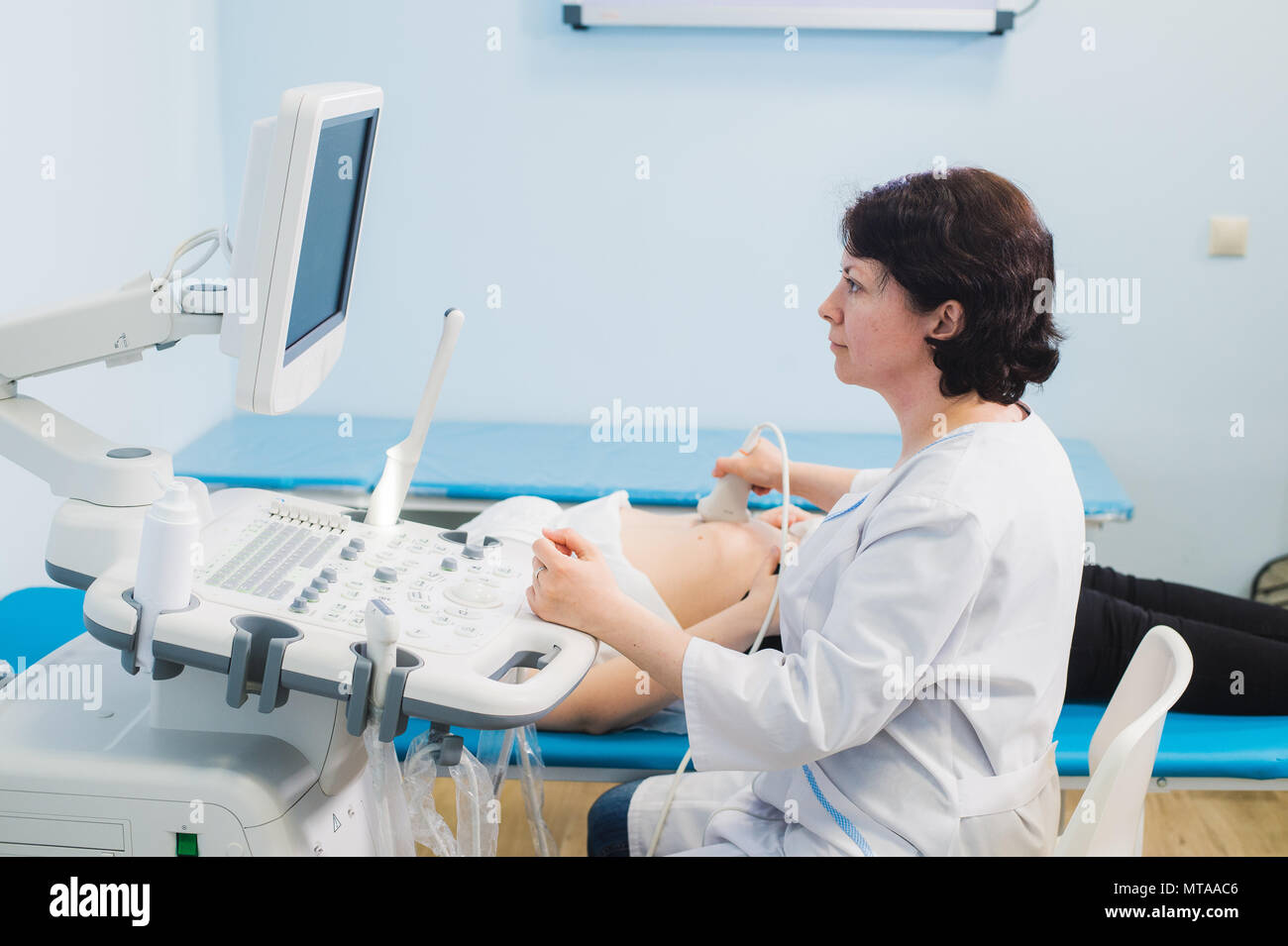 Happy mature female doctor using ultrasound scanner. Echography machine ...