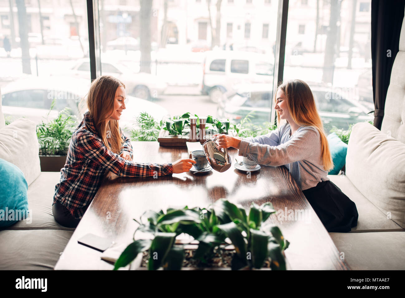 Two girlfriends met in a cafe to drink coffee. Female friends sitting ...