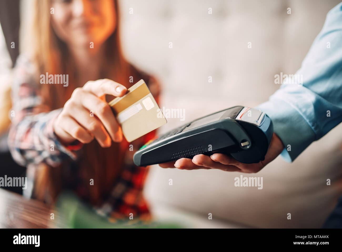 Young woman paying with credit card in cafe, waiters hand with terminal ...
