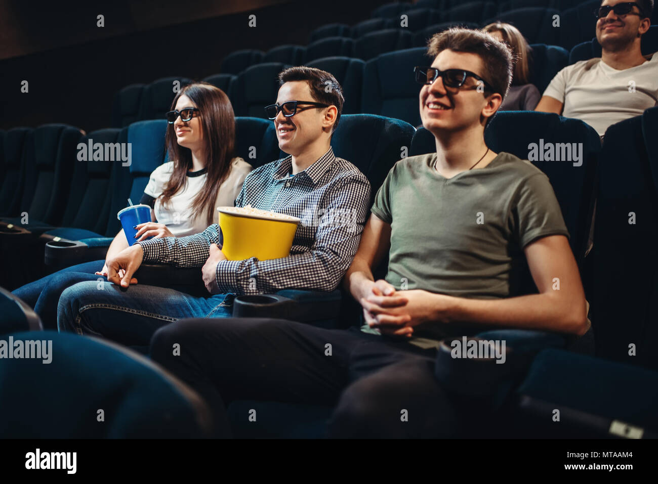 People in 3d glasses with popcorn and drinks watching movie in cinema ...