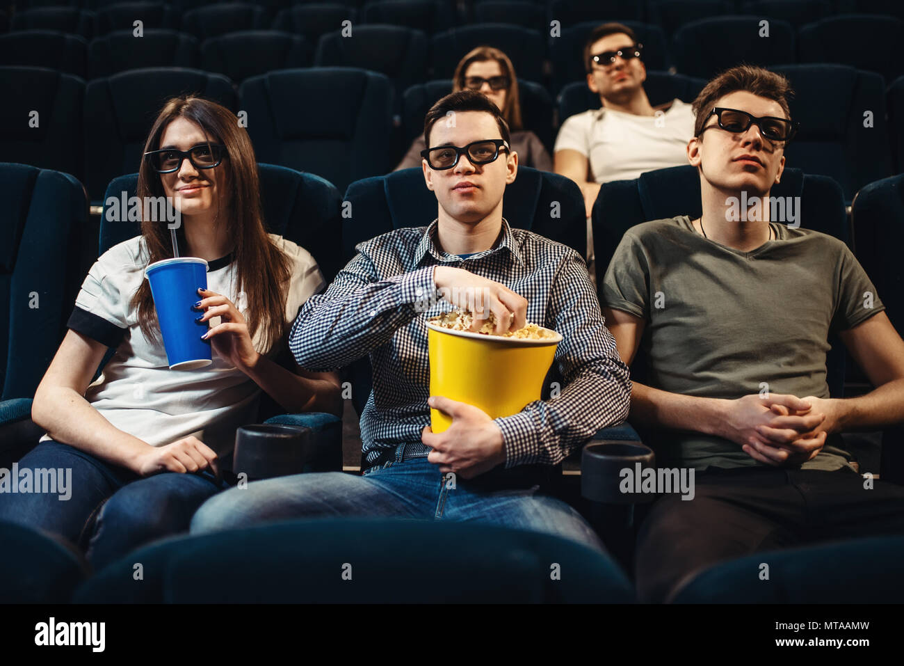 People in 3d glasses with popcorn and drinks watching movie in cinema ...