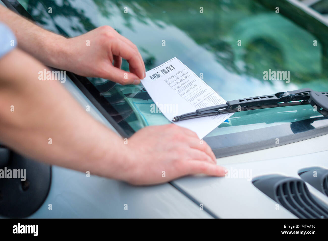 Man finding a ticket fine under the car windscreen because of parking ...