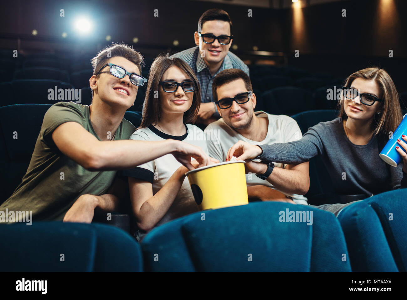 Happy friends with popcorn and drinks watching movie in cinema ...