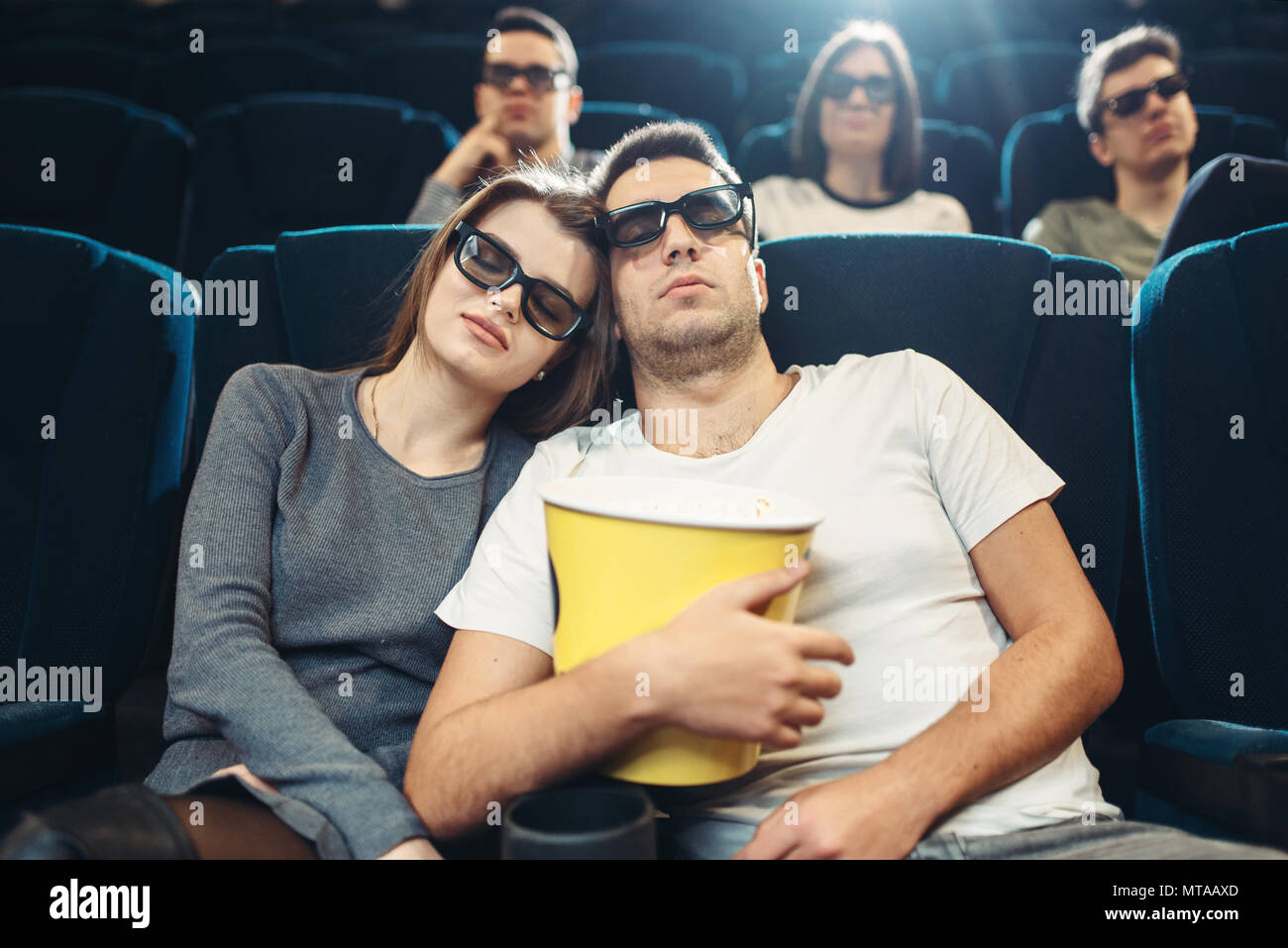 Young man with popcorn sleeping in cinema. Boring film concept, people ...