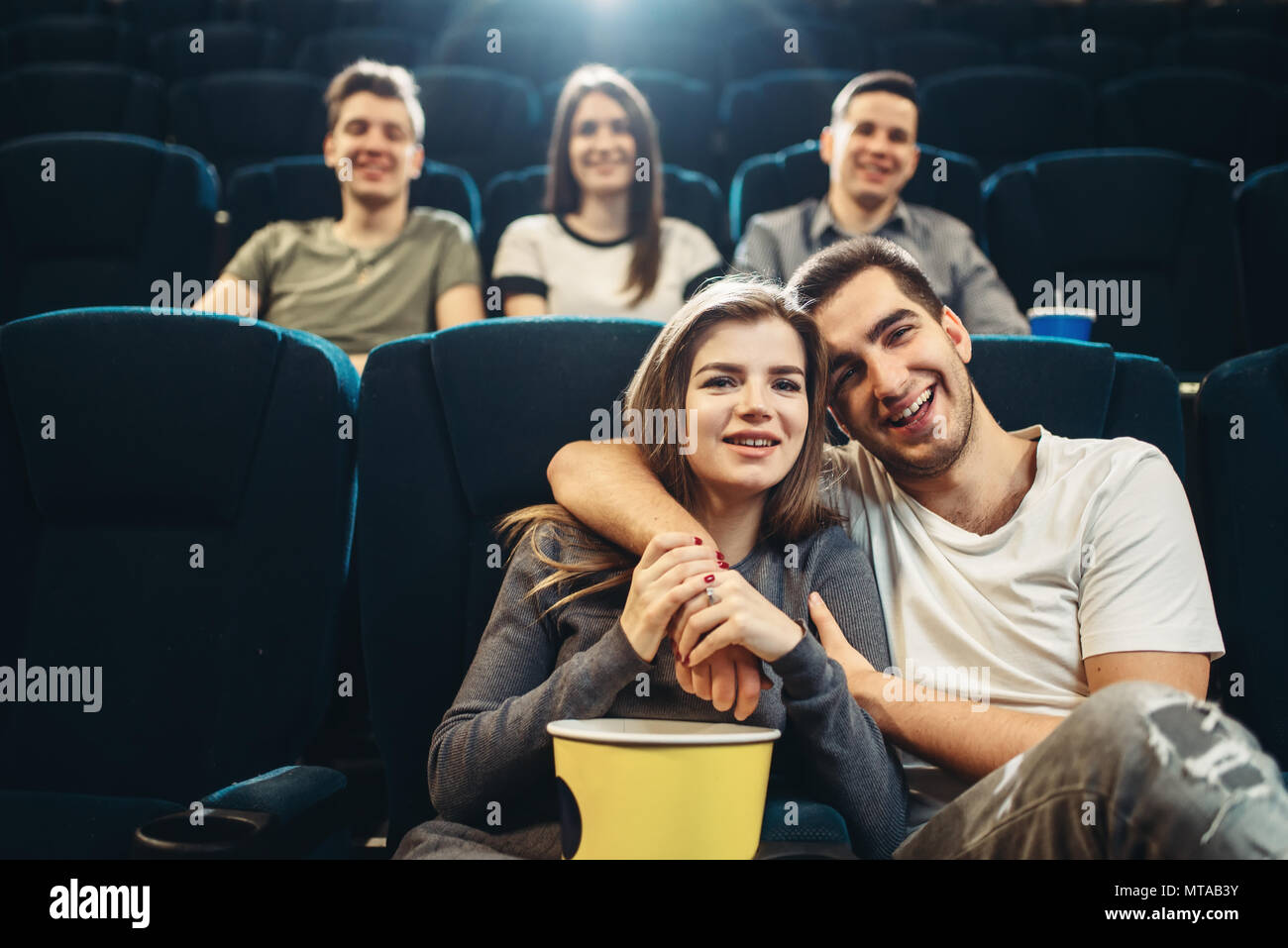 Young smiling man hugs his woman in cinema. Showtime, entertainment ...