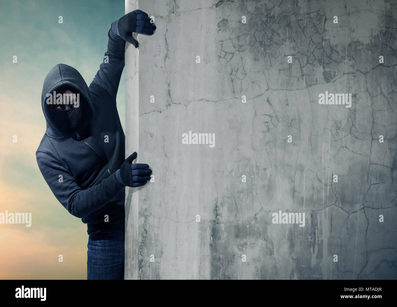 Robber hiding behind a empty wall with space for text Stock Photo - Alamy