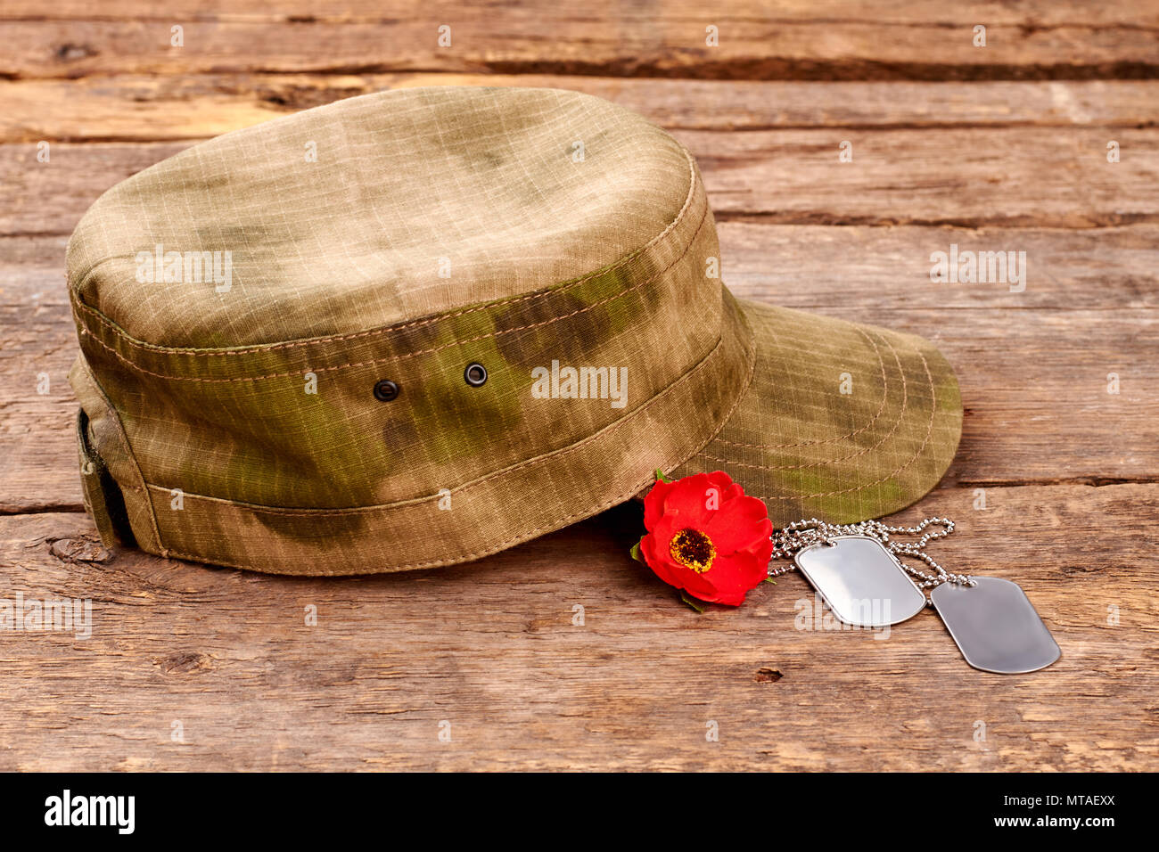 Military cap, red poppy and dog tags. Wooden desk surface background ...
