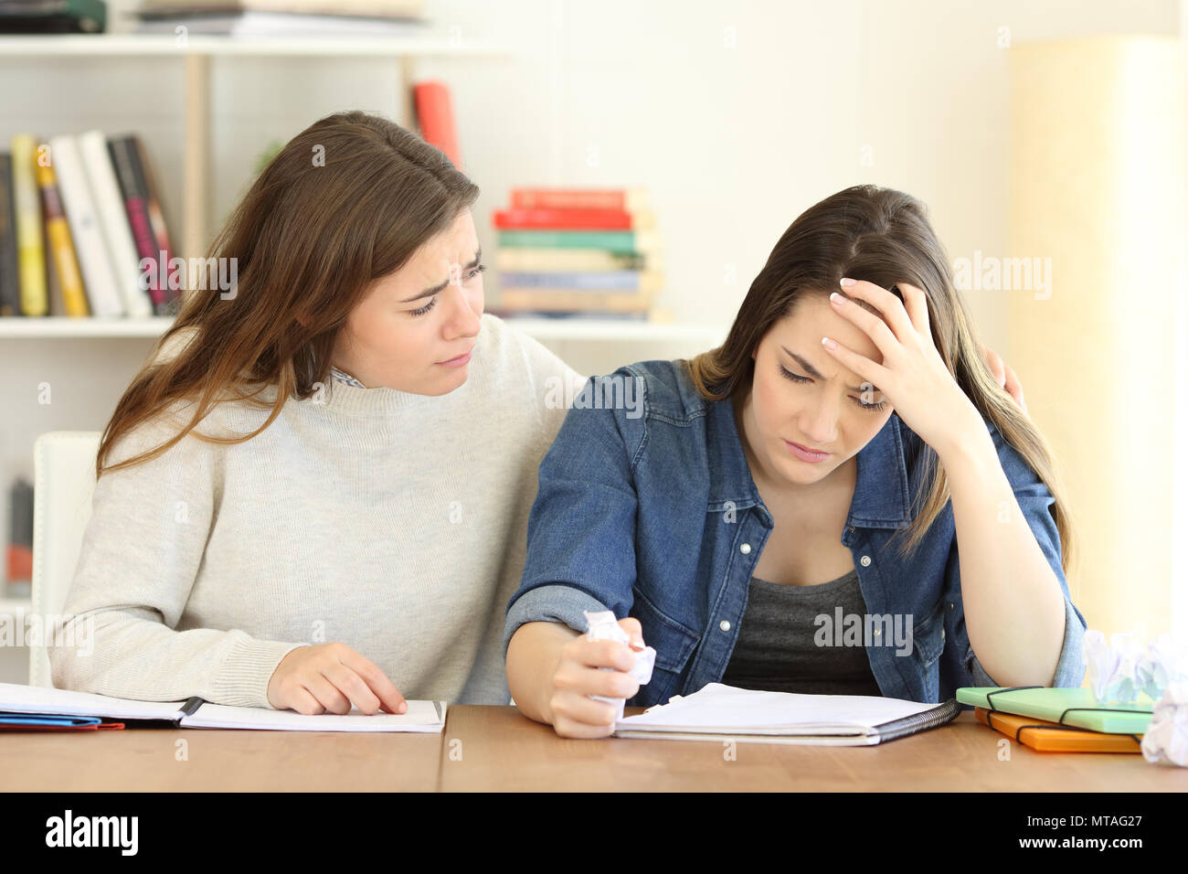 Student comforting her frustrated friend uncapable to learn a lesson ...