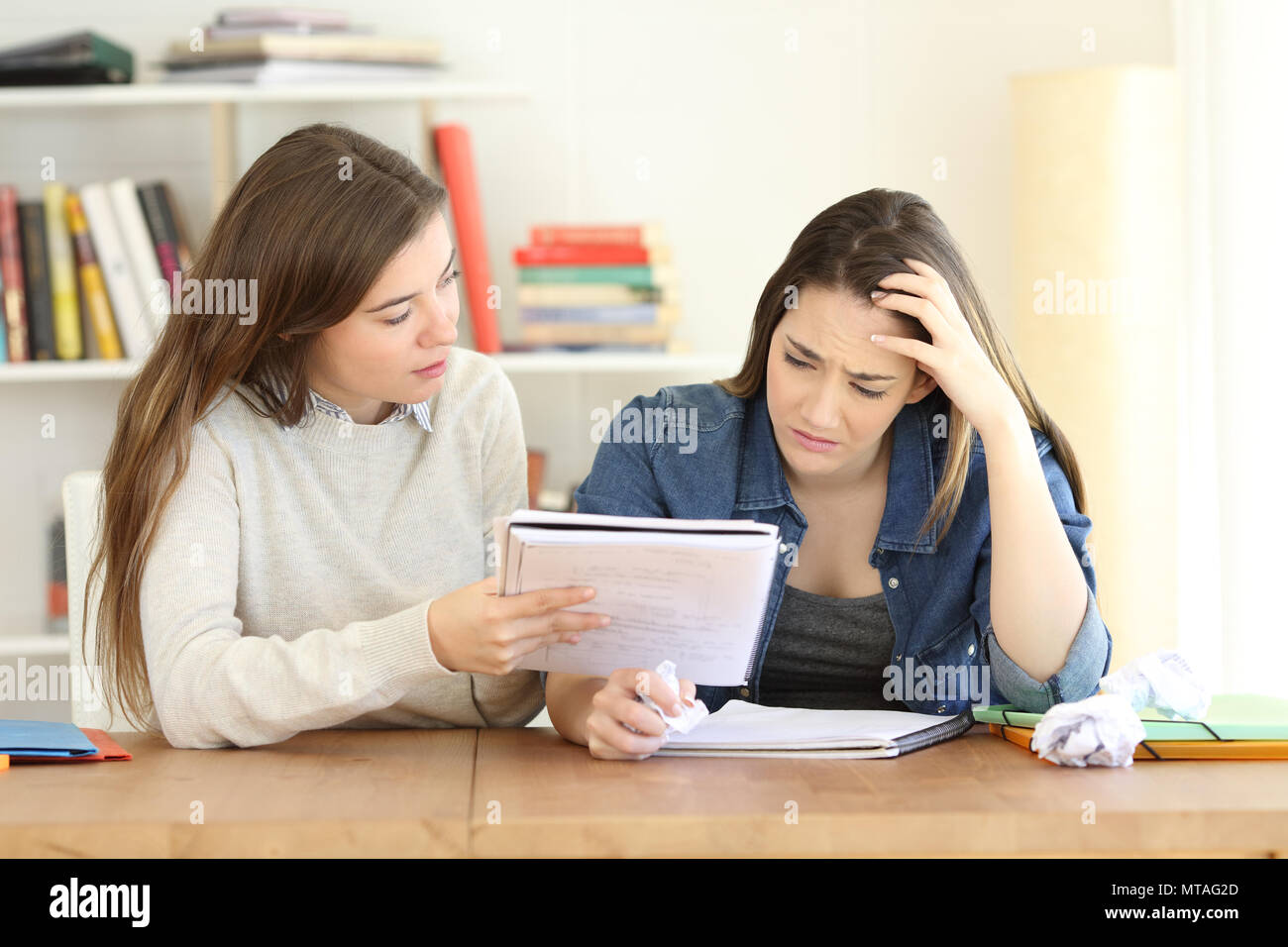 Student helping her frustrated friend to learn a difficult lesson on a ...