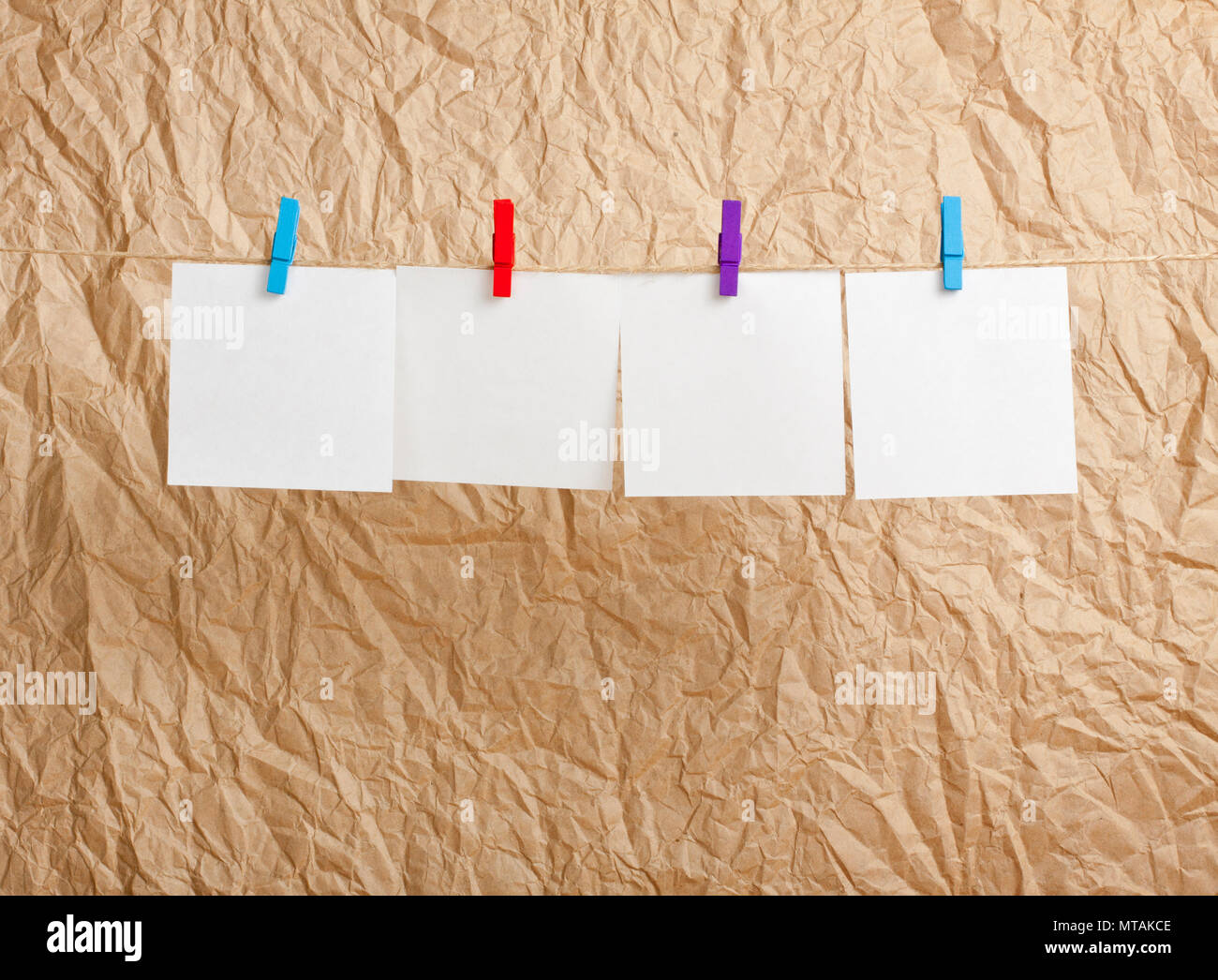 Four white blank notes hanging on the clothesline on craft paper ...