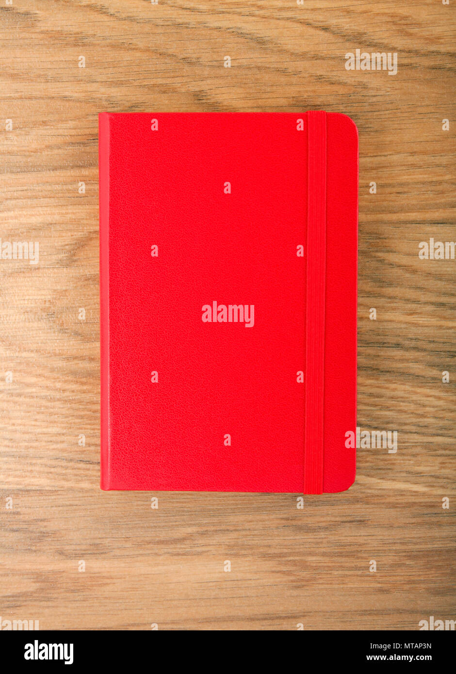 Red copybook with elastic band on wooden background Stock Photo - Alamy