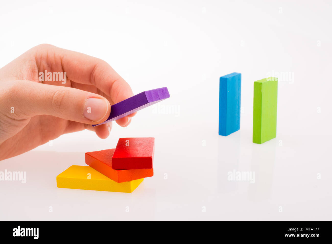 Hand playing with colored domino on white background Stock Photo - Alamy