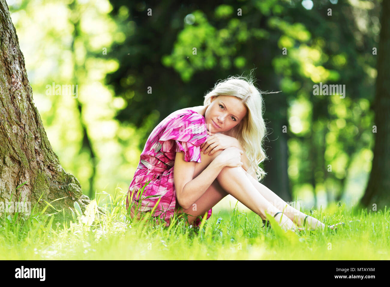 Beautiful Woman sitting under tree in spring park Stock Photo - Alamy