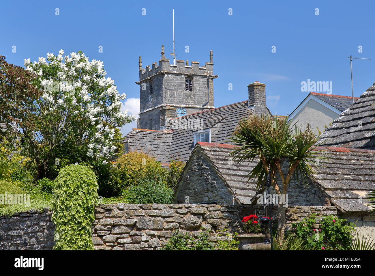 The Tower of St Edward's Church with flagstone roofs and lilac tree in ...