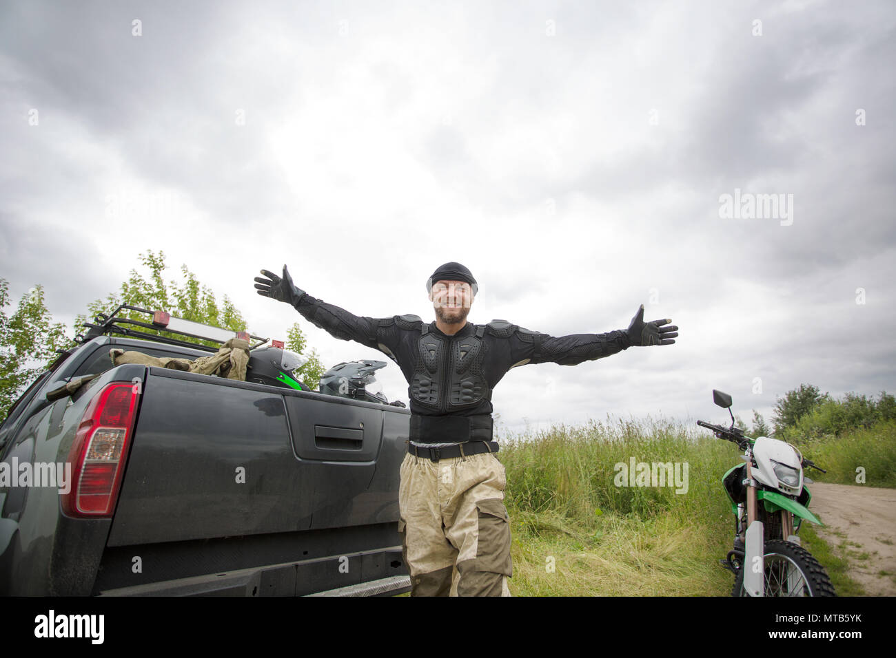 Happy smiling young man with arms wide open outdoors wearing mot Stock ...