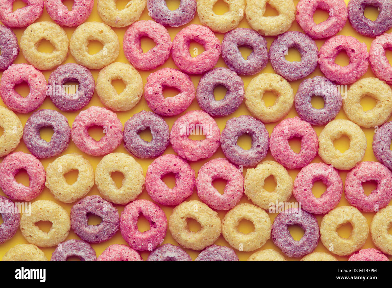 Top view of colorful cereal rings on yellow background Stock Photo - Alamy