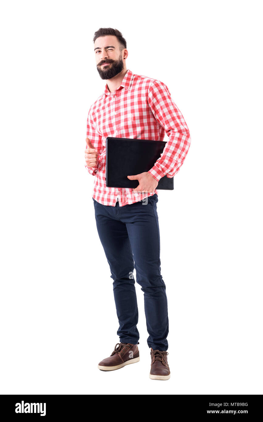 Satisfied winking bearded business man with laptop under arm holding ...