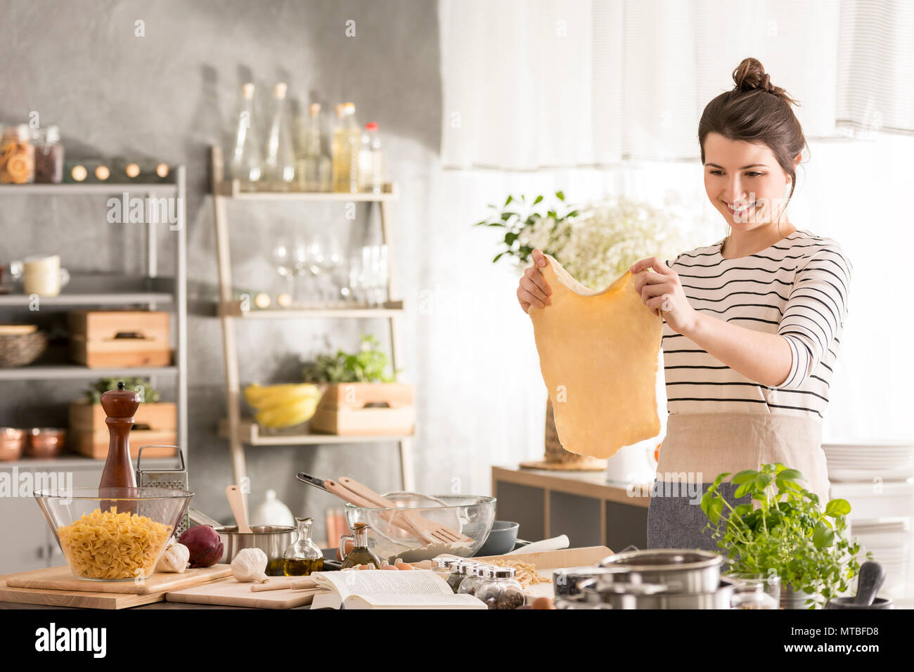 Happy young woman making pizza in her modern kitchen Stock Photo - Alamy