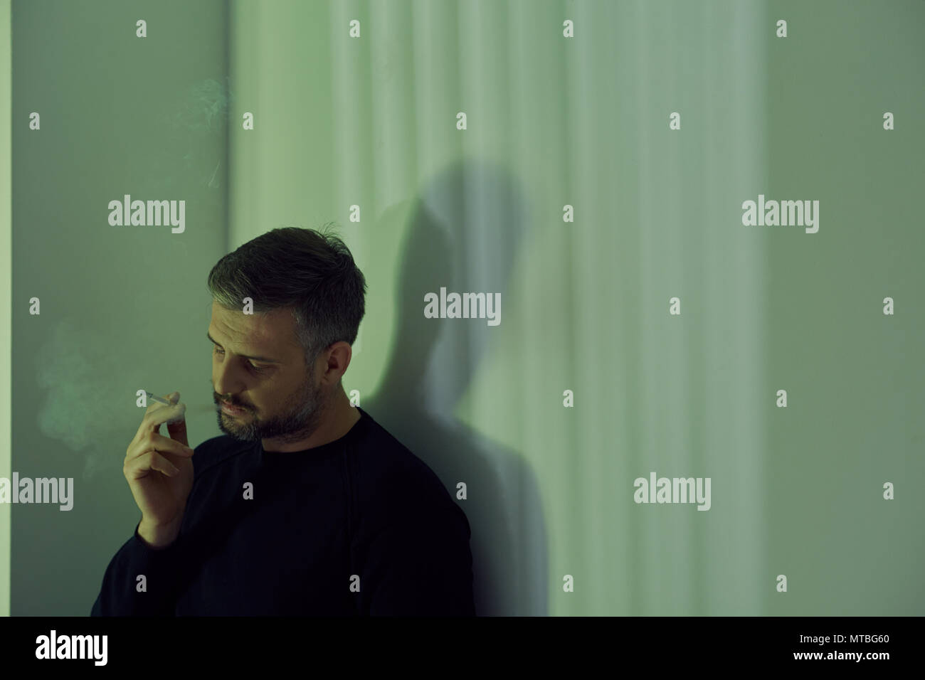 Man with cigarette in gloomy room interior Stock Photo - Alamy