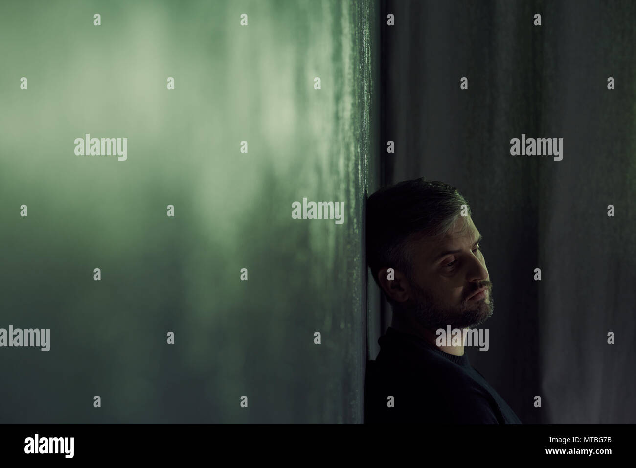 Lonely man sitting alone in gloomy room Stock Photo - Alamy