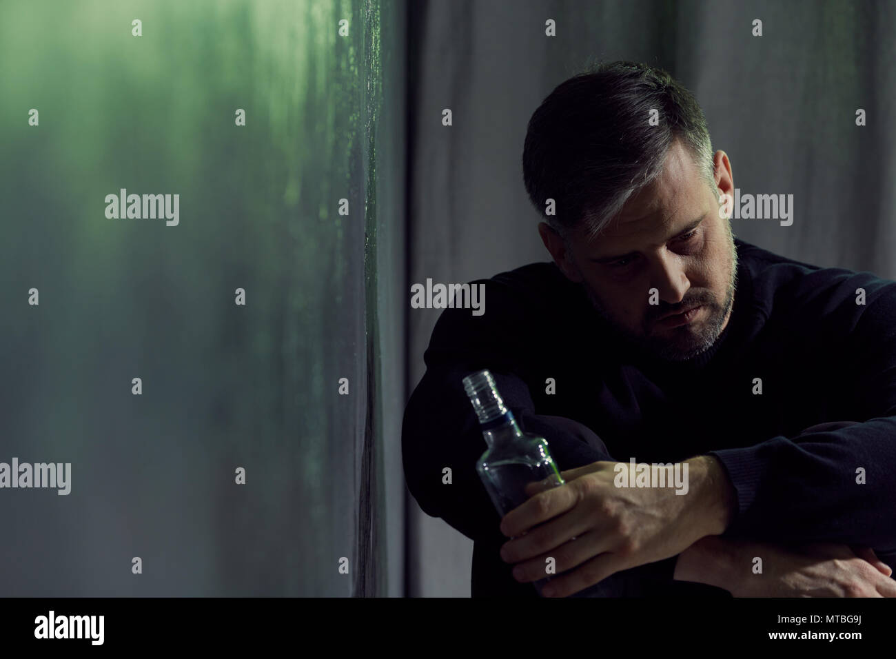 Alcohol addicted man sitting alone with alcohol bottle Stock Photo - Alamy