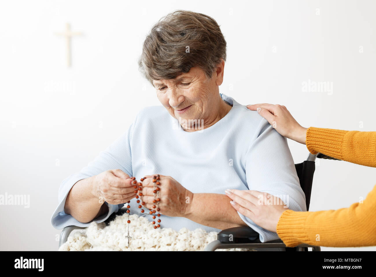 Person supporting disabled elderly woman praying with rosary at home ...