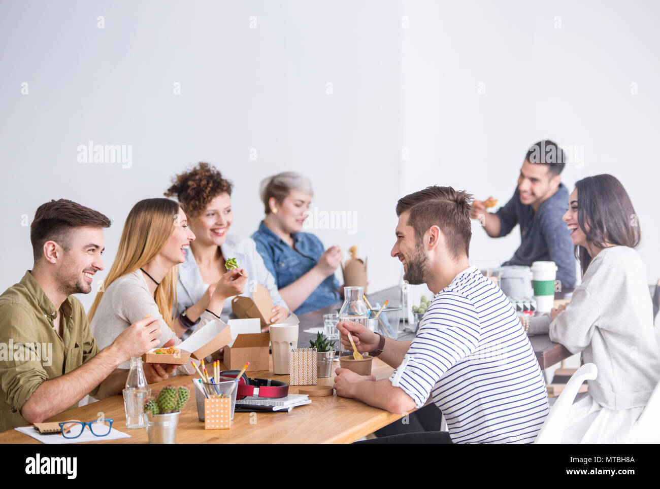 Multicultural team of coworkers eating a healthy lunch together at the ...