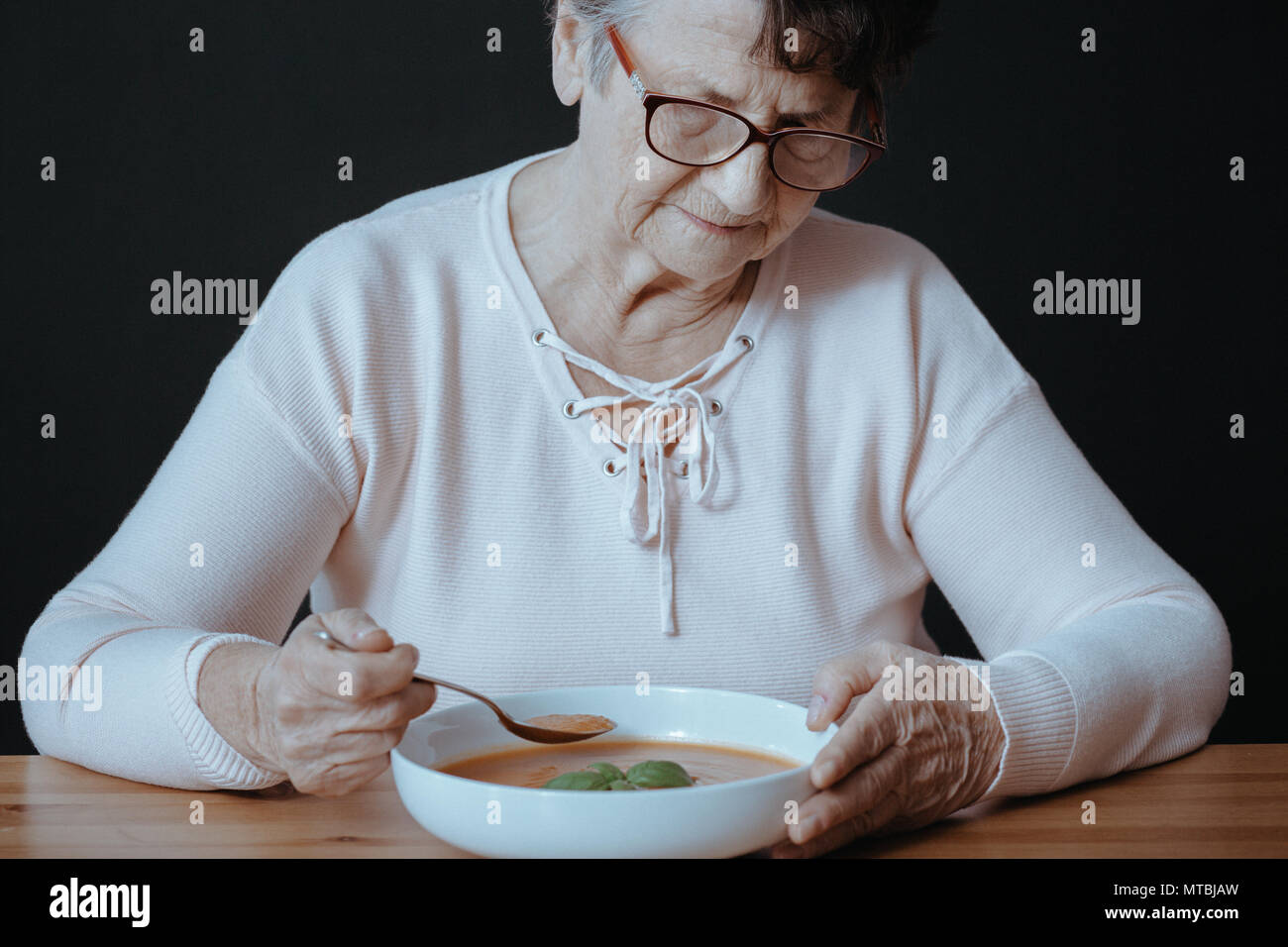Senior woman suffering from inappetence, sitting beside table Stock ...