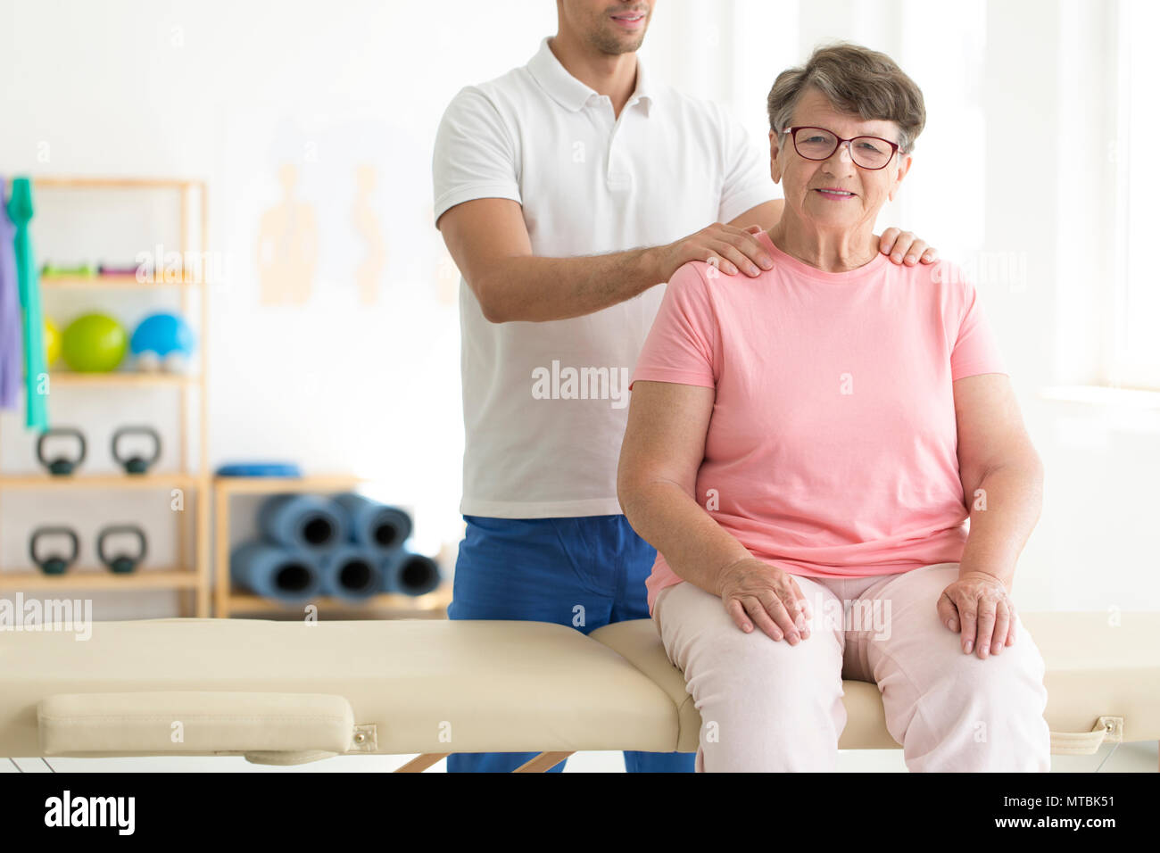 Committed elderly lady being rehabilitated by a physiotherapist on ...
