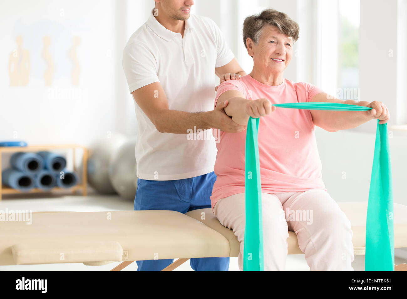 Elderly woman doing active pnf exercises with a teal scarf as a part of ...