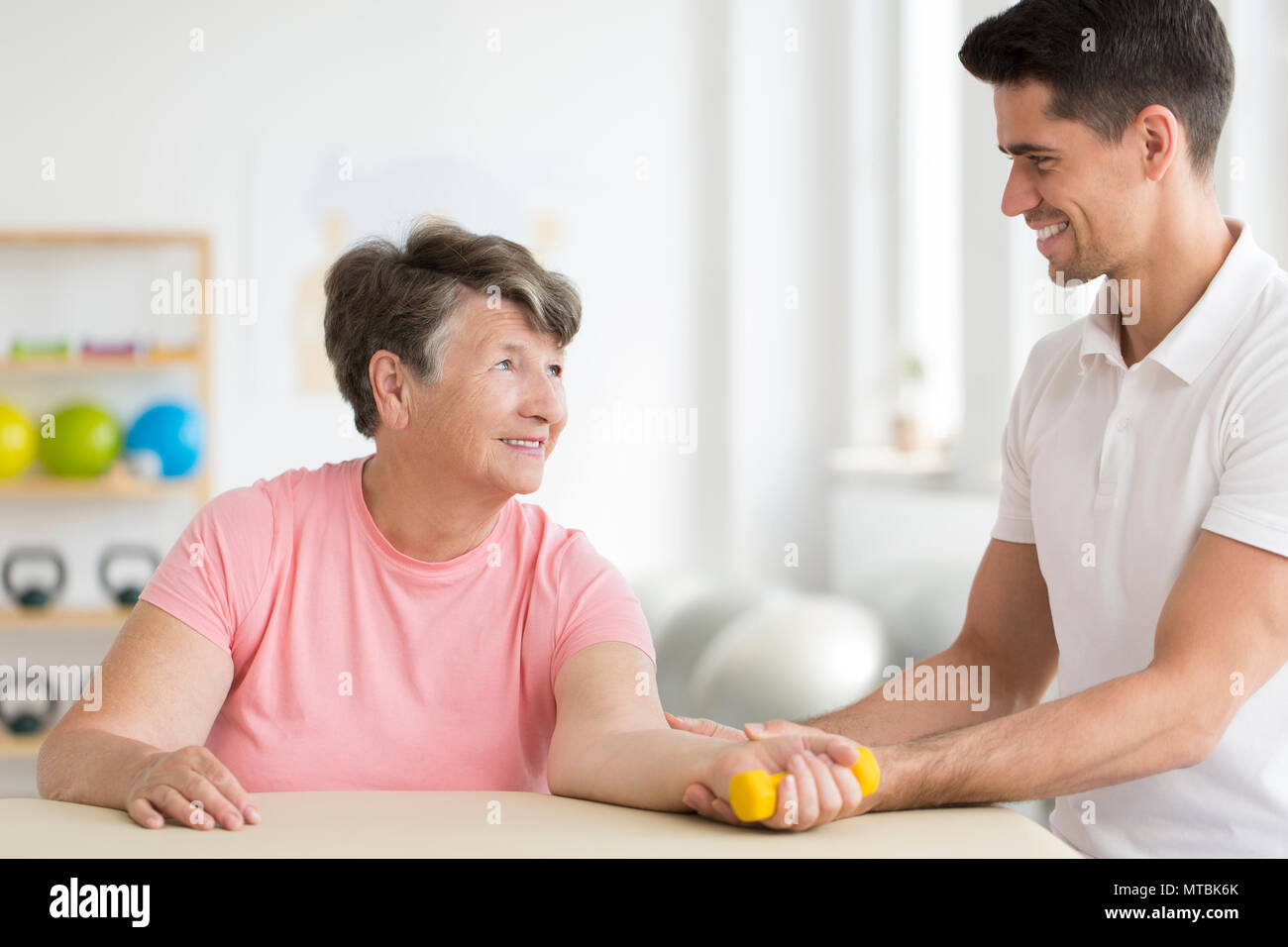 Physical therapist supporting his elderly ward in an isometric set of ...