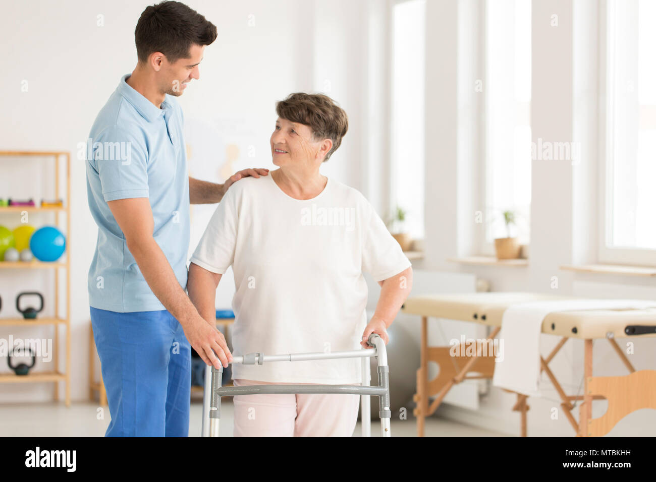 Elderly ward using a walking frame to support herself during ...